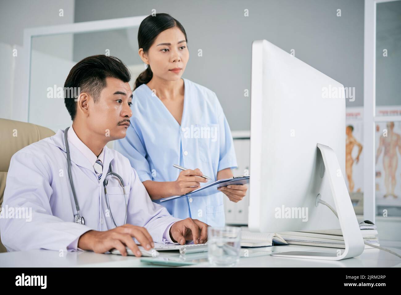 Vietnamese doctor and nurse reading information on computer screen ...