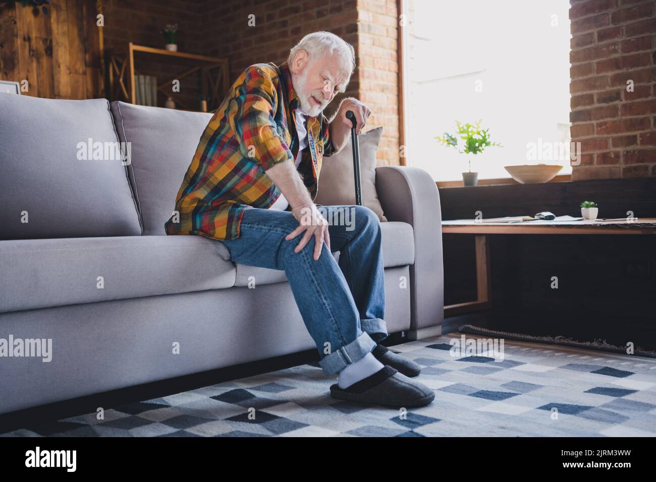 Photo of upset sad retired man dressed plaid shirt having leg ache ...