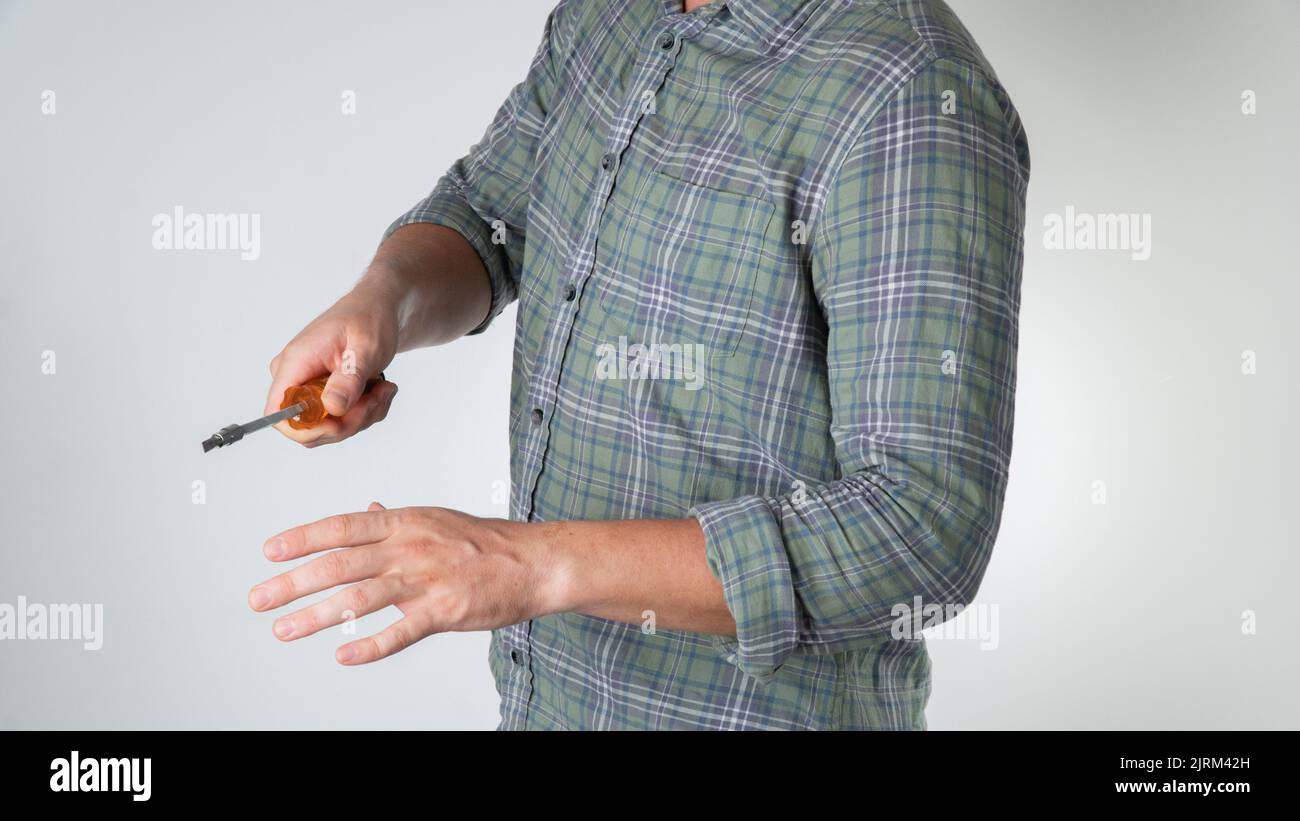 A man with a screwdriver in his hand gesture screws a close-up screw on ...