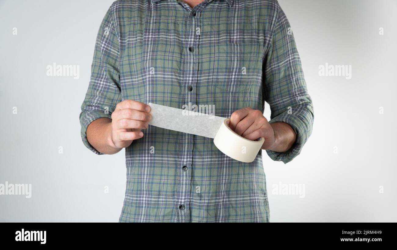 A man tears off a ribbon of white wide tape on a white background Stock ...