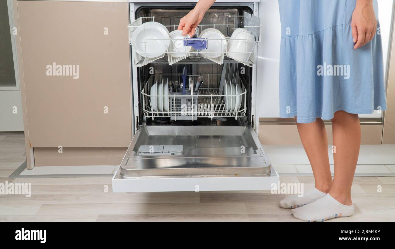 A woman takes clean dishes out of the dishwasher Stock Photo - Alamy