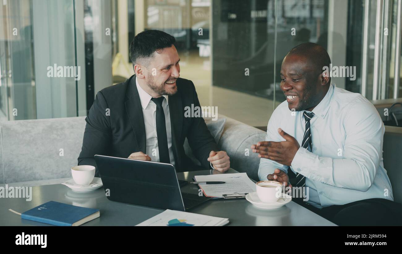 Two businessmen talking ang laughing in modern cafe. Men having fun and ...