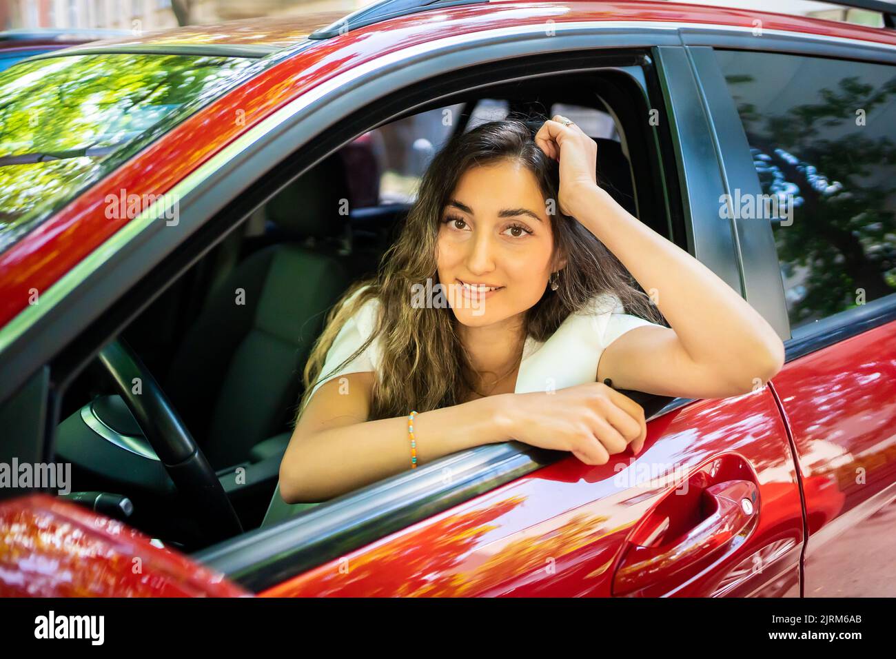 Happy smiling woman driver behind the wheel red car. View through car ...