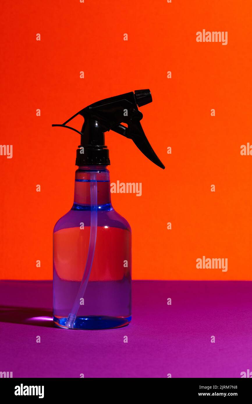 A vertical shot of a transparent sprayer bottle on a bold vibrant ...