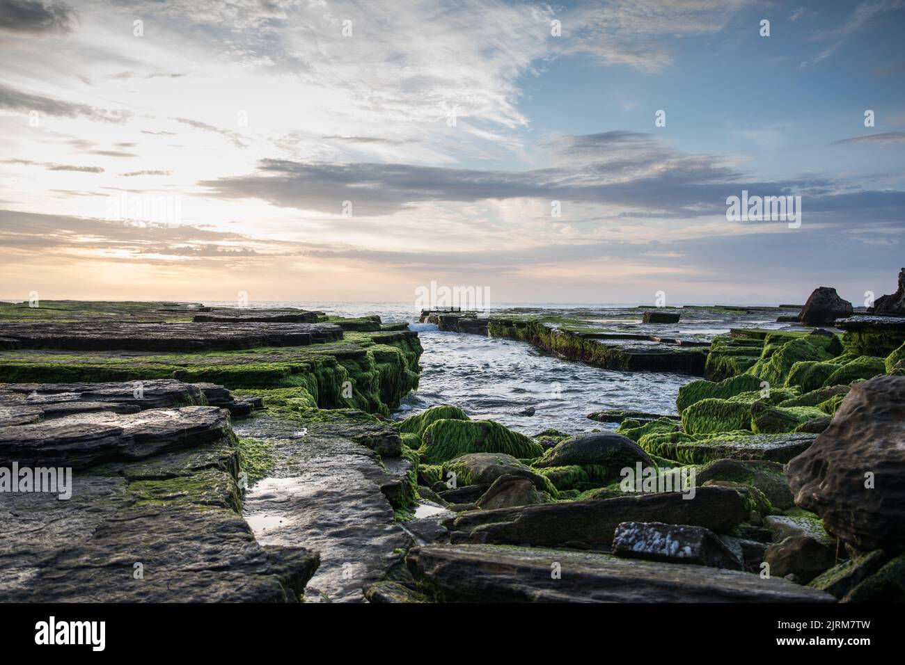 A beautiful scenic view of rocks on a beach at sunset Stock Photo - Alamy