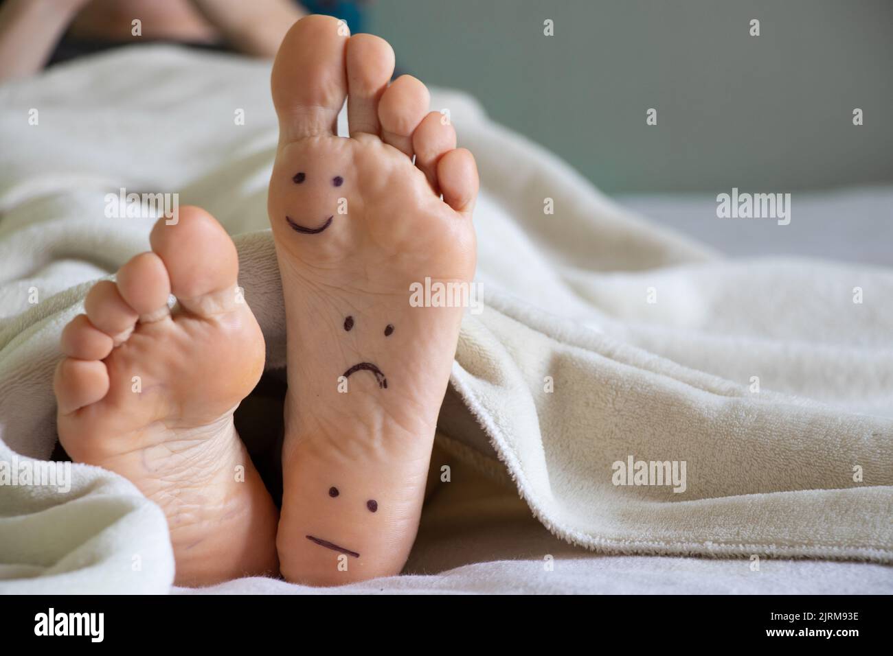 a smile and sad emoticons are drawn on the girl s leg, legs on the bed ...