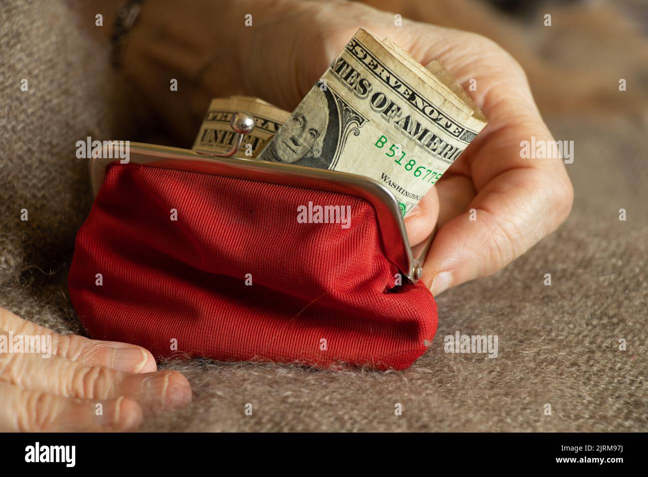 old woman's hands take out a dollar bill from a soft red wallet, money ...