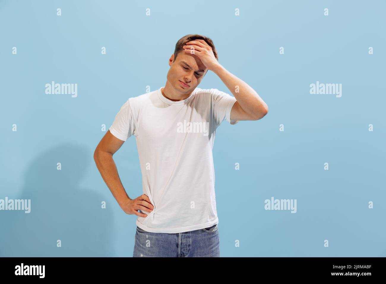 Portrait of young man holding palm on forehead, posing isolated over ...