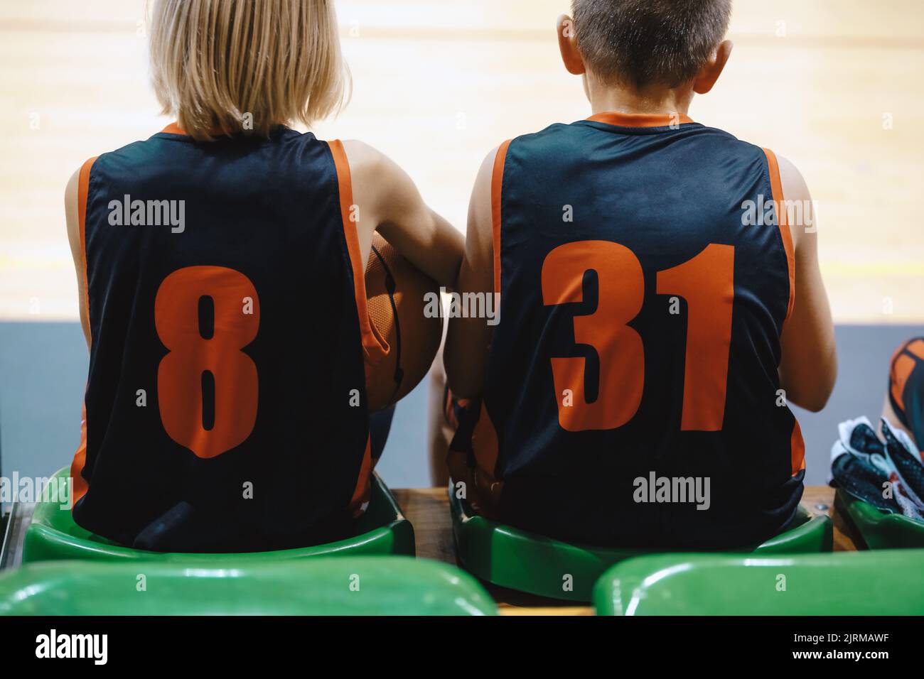 Two boys in basketball team sitting on substitute players bench ...