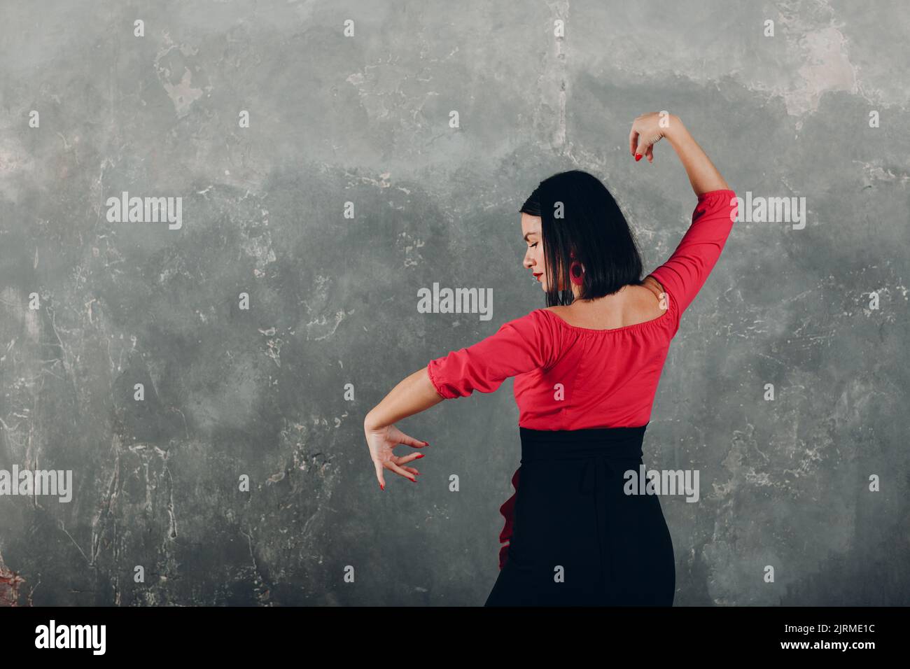 Young adult spanish woman dancing flamenco on gray vintage studio ...