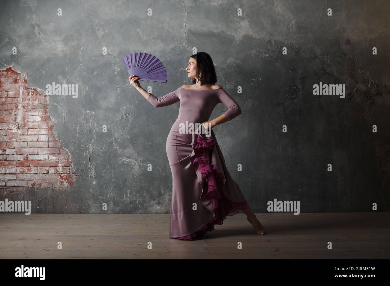 Young adult spanish woman dancing flamenco on gray vintage studio ...