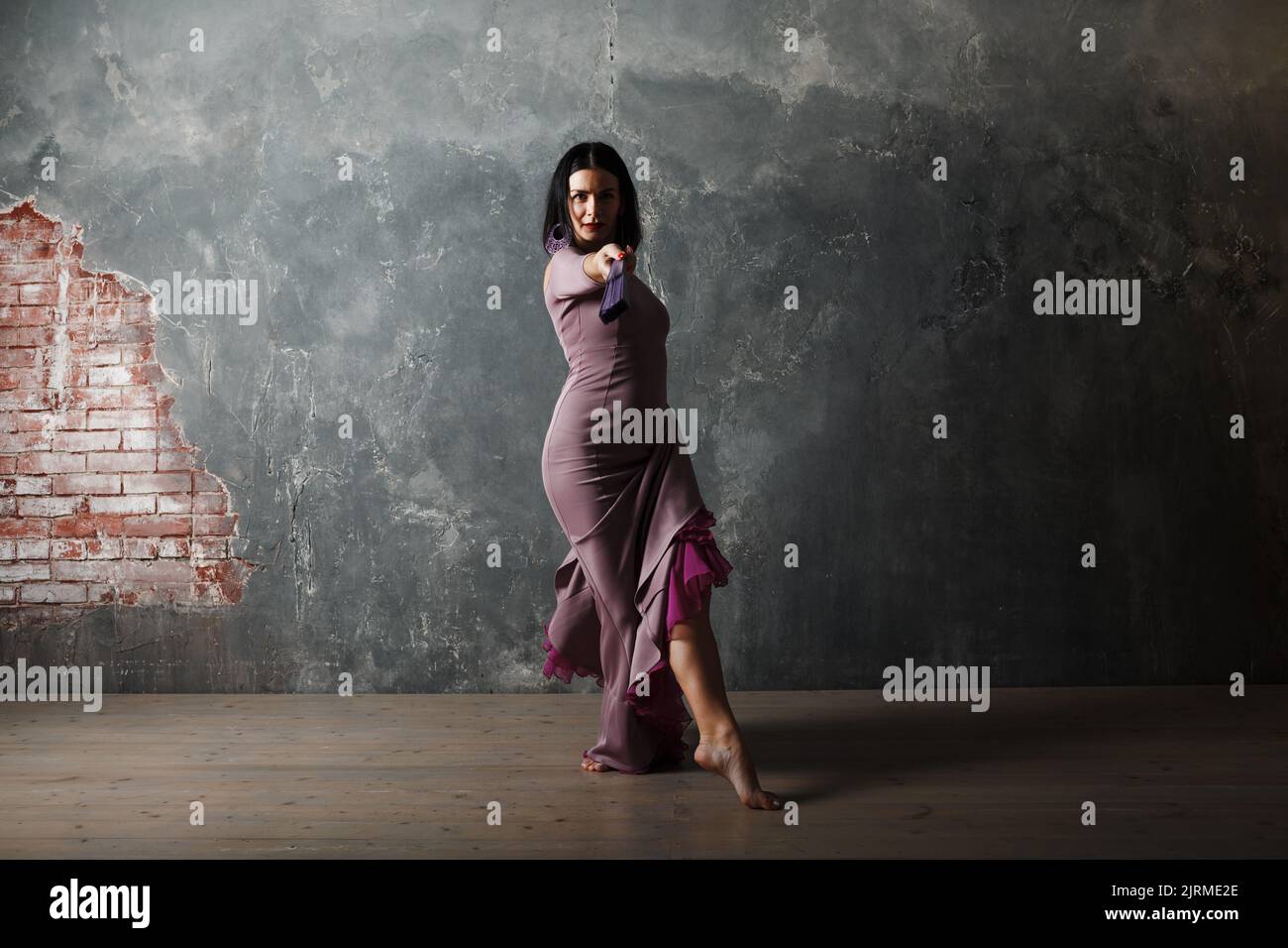 Young adult spanish woman dancing flamenco on gray vintage studio ...