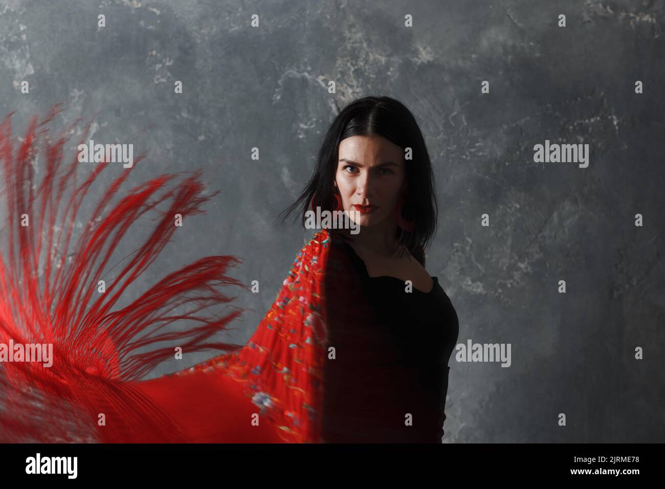 Young adult spanish woman dancing flamenco on gray vintage studio ...