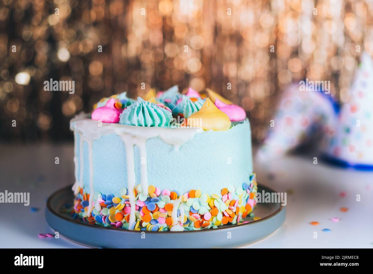 Colorful birthday cake with sprinkles and festive caps on the sparkling ...