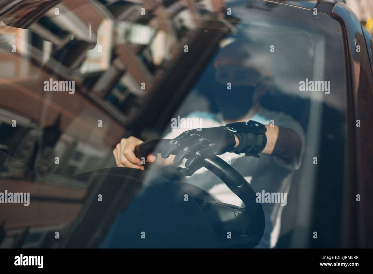Young disabled man driver with artificial prosthetic hand driving ...