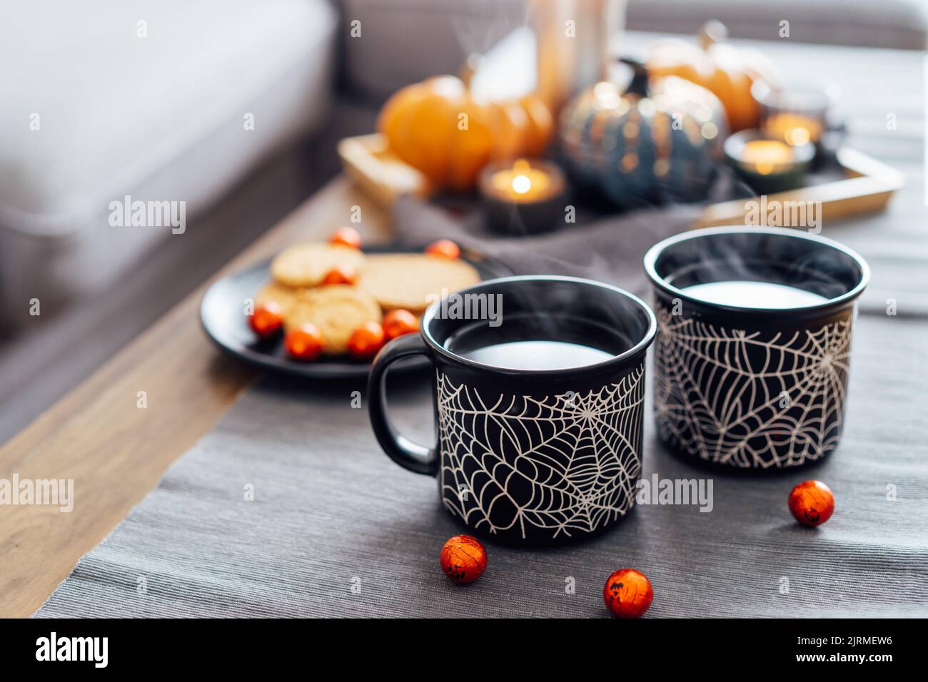 Cozy halloween plans at home. Hot tea drink in black mugs with spider ...