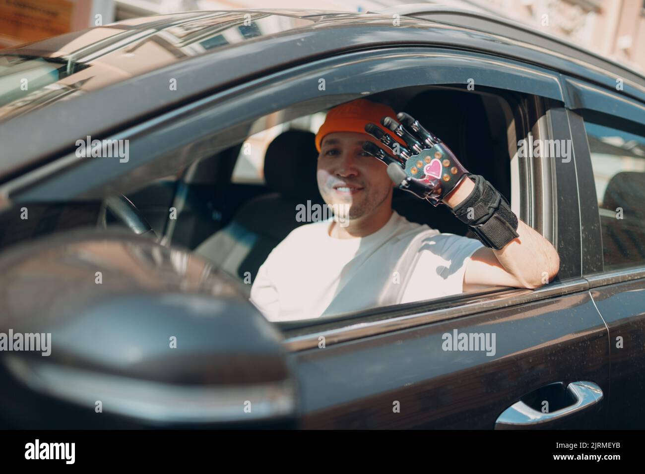 Young disabled man driver with artificial prosthetic hand driving ...