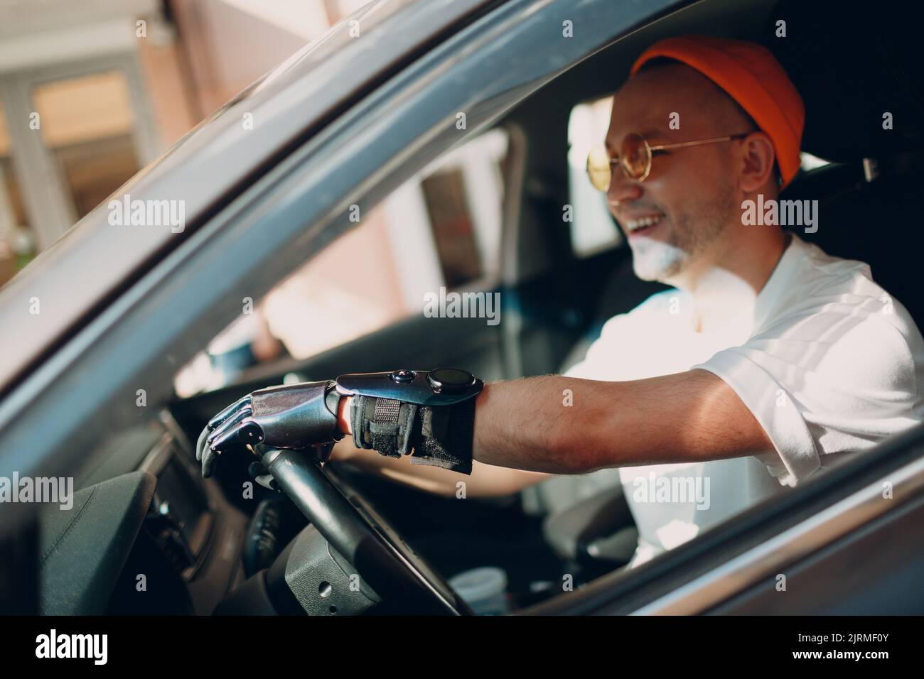 Young disabled man driver with artificial prosthetic hand driving ...