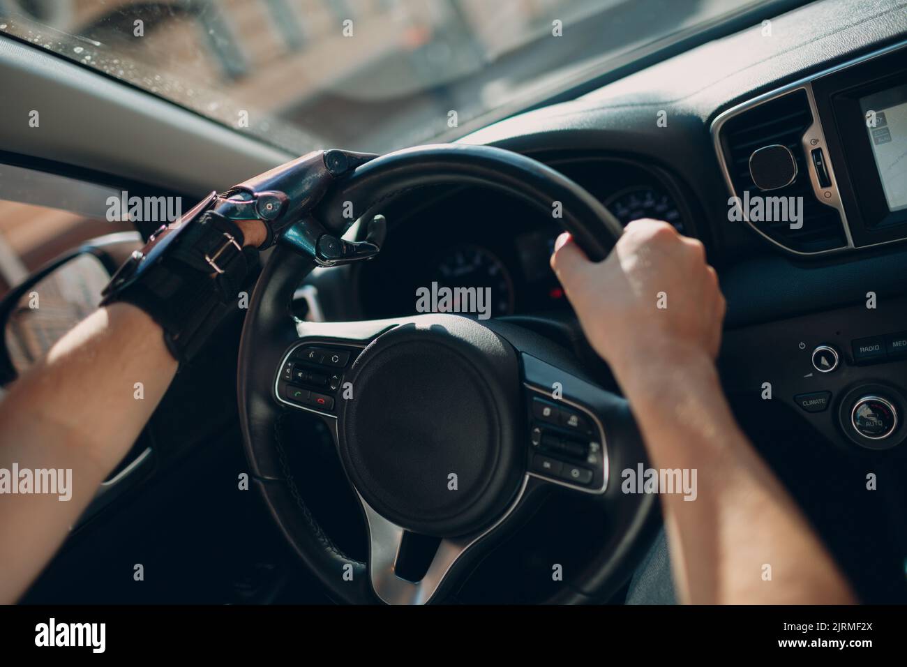 Young disabled man driver with artificial prosthetic hand driving on ...