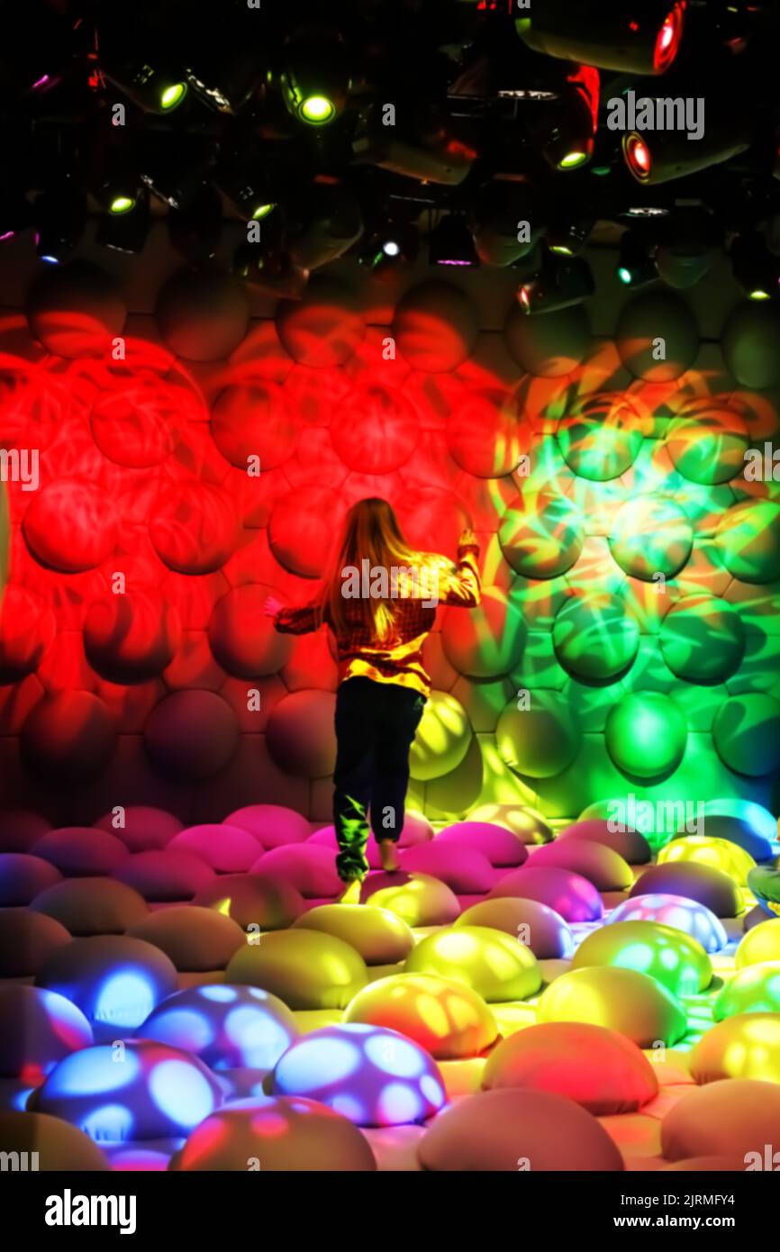 A woman jumps on soft pimples in a bright multi-colored anti-stress ...