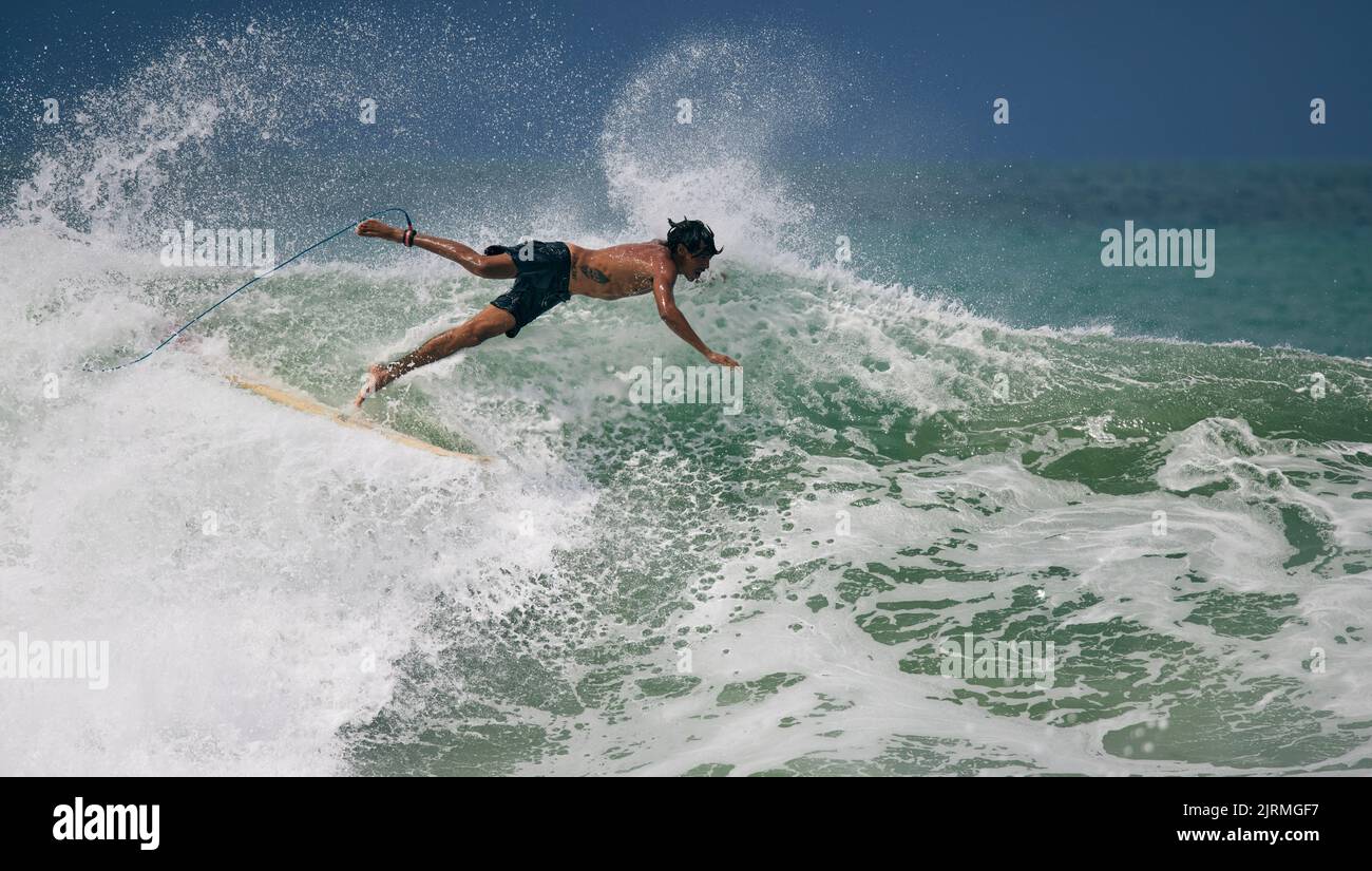 The view of a male surfer jumping into the water waves under the blue ...
