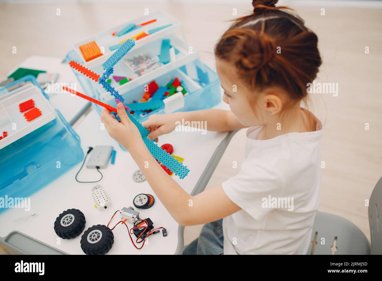 Smiling kid little girl child constructor checking technical toy ...