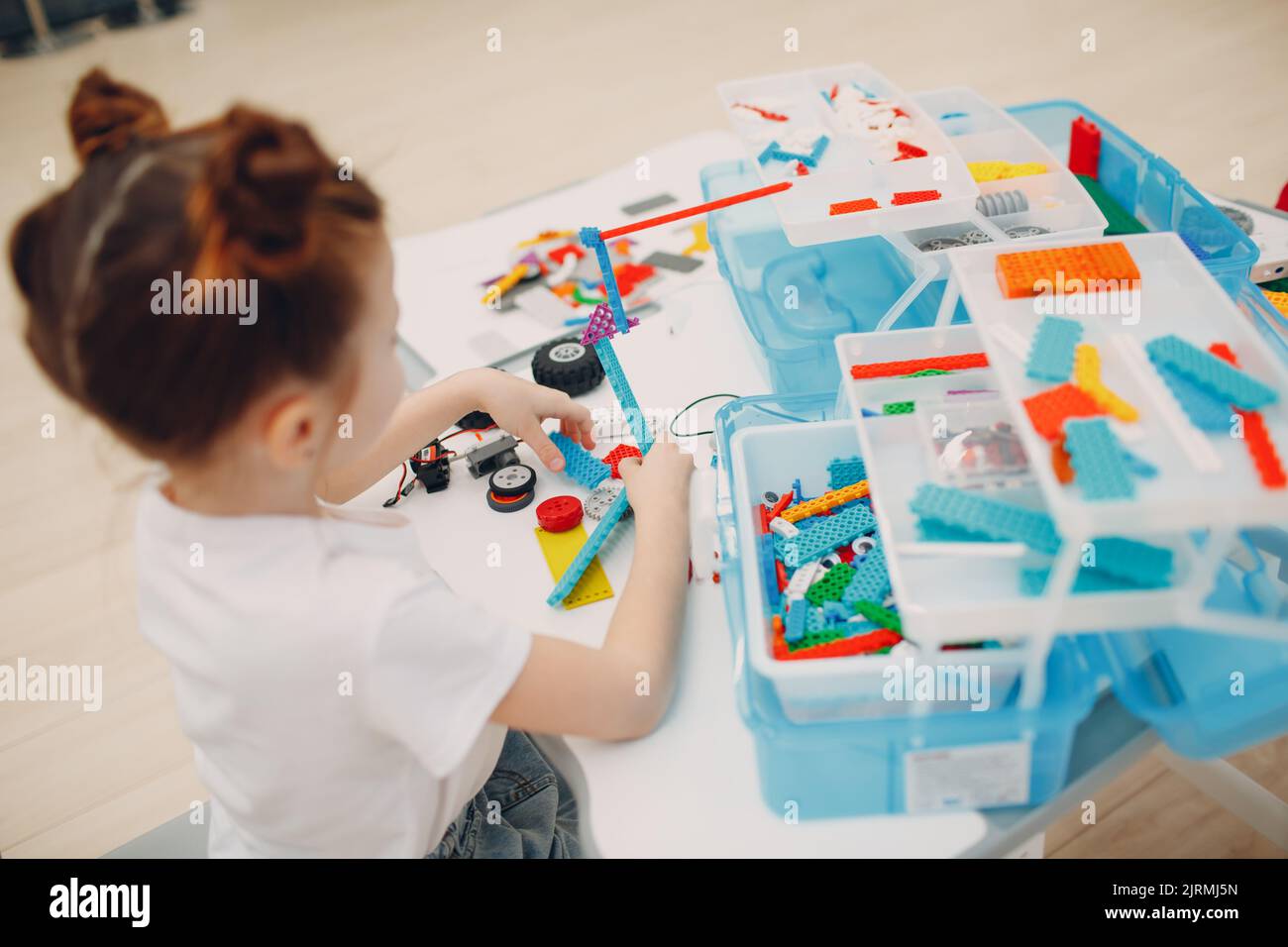 Smiling kid little girl child constructor checking technical toy ...