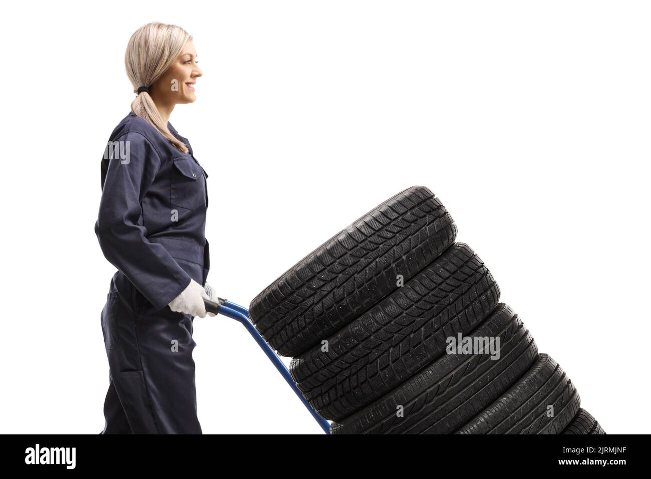 Female auto mechanic walking and pushing tires on a hand-truck isolated ...