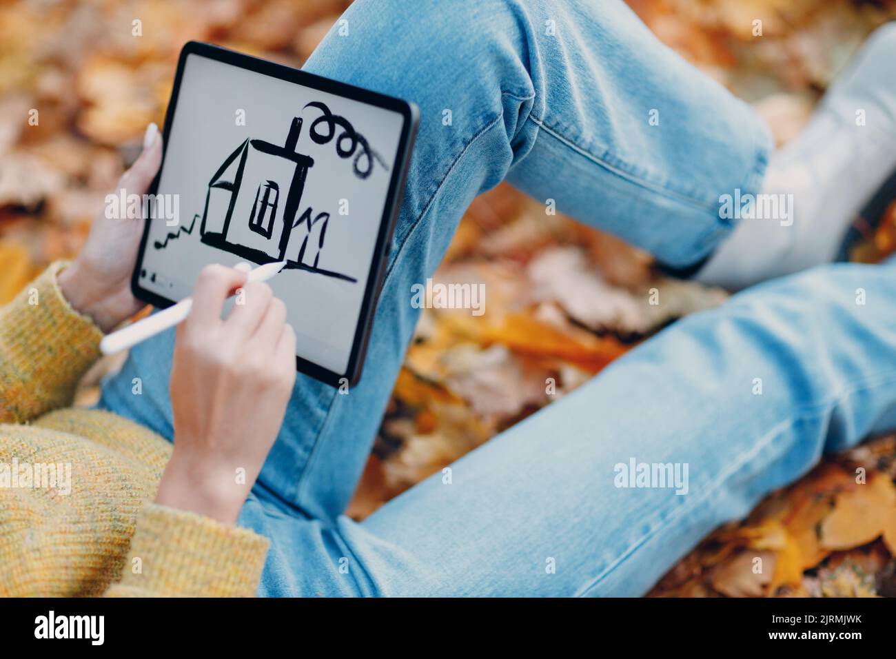 Young woman model sitting with tablet pc and painting with pencil ...