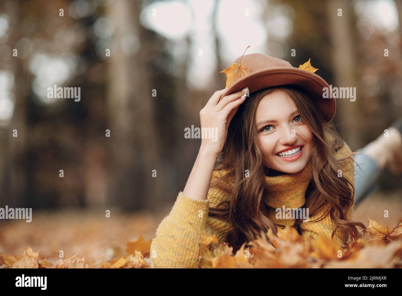 Young woman model lying in autumn park with yellow foliage maple leaves ...