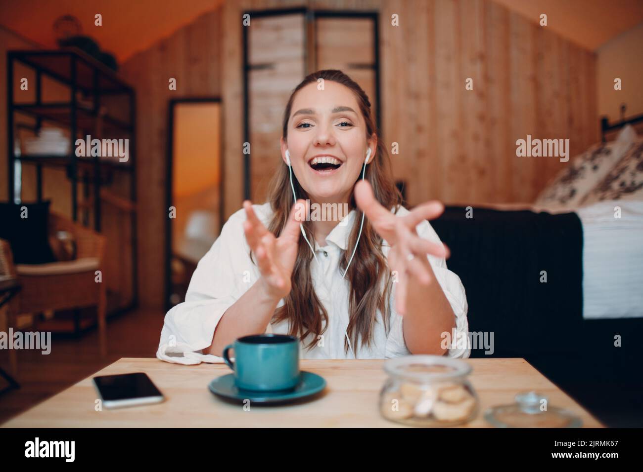 Smiling happy young woman sitting at table at home behind computer ...