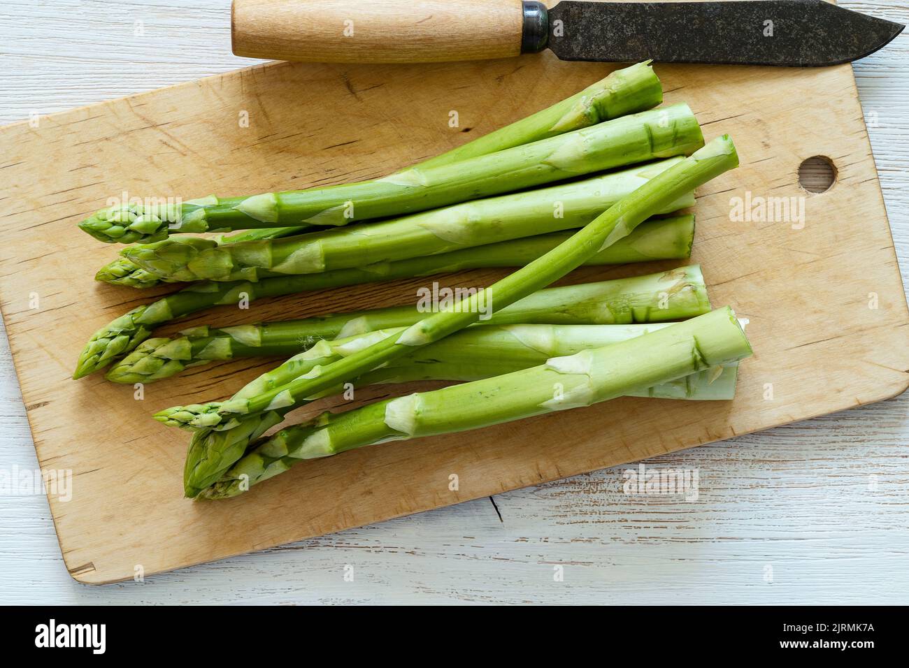 Raw organic green asparagus knife on cutting board, top view. Plant ...