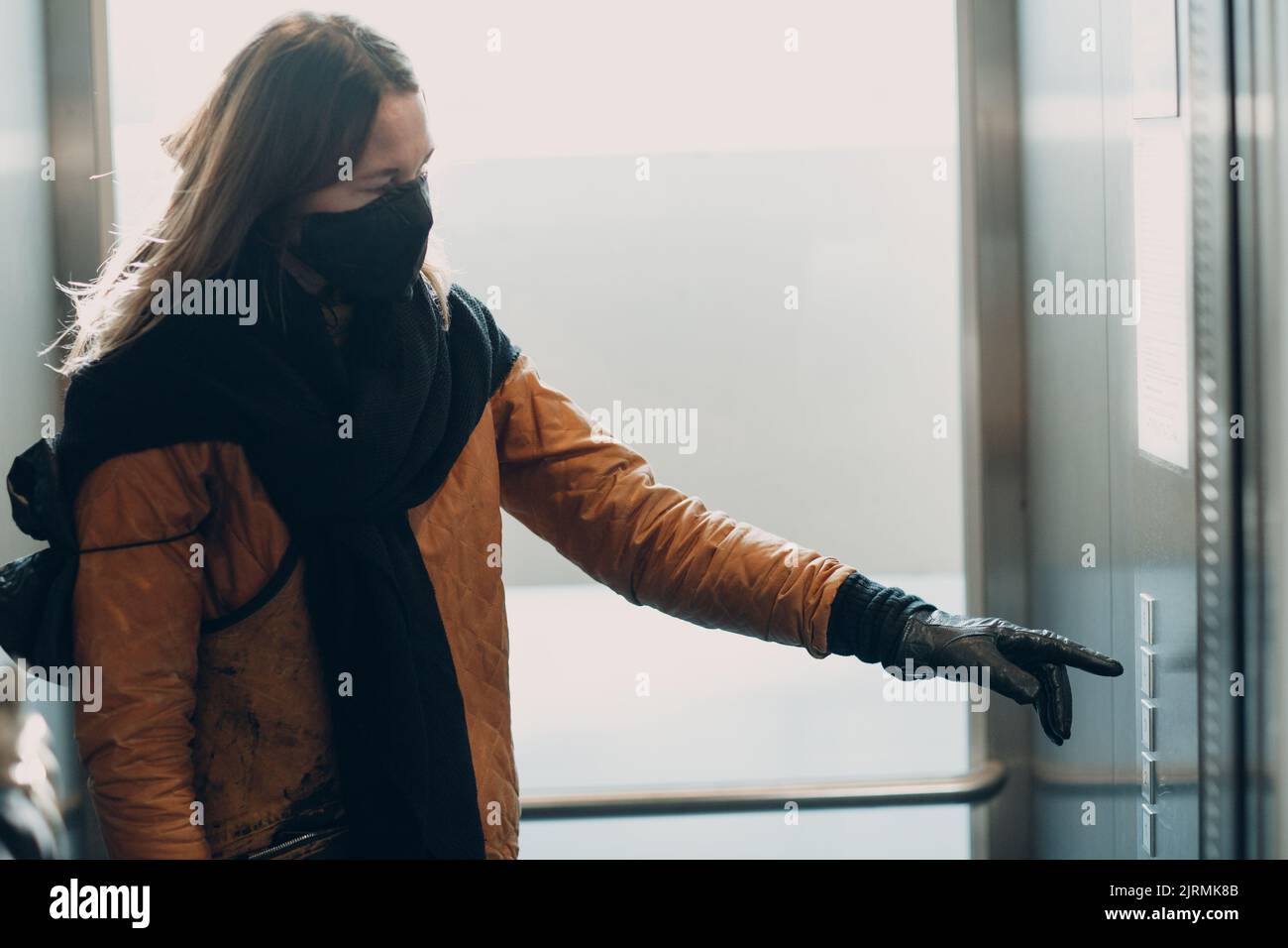 Woman in face medical mask with hand in glove forefinger pressing the ...