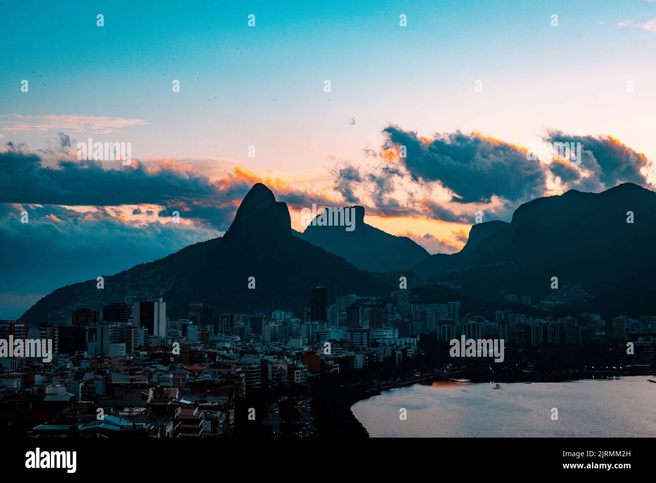 The coastline tropical city buildings and mountains under the sunset ...