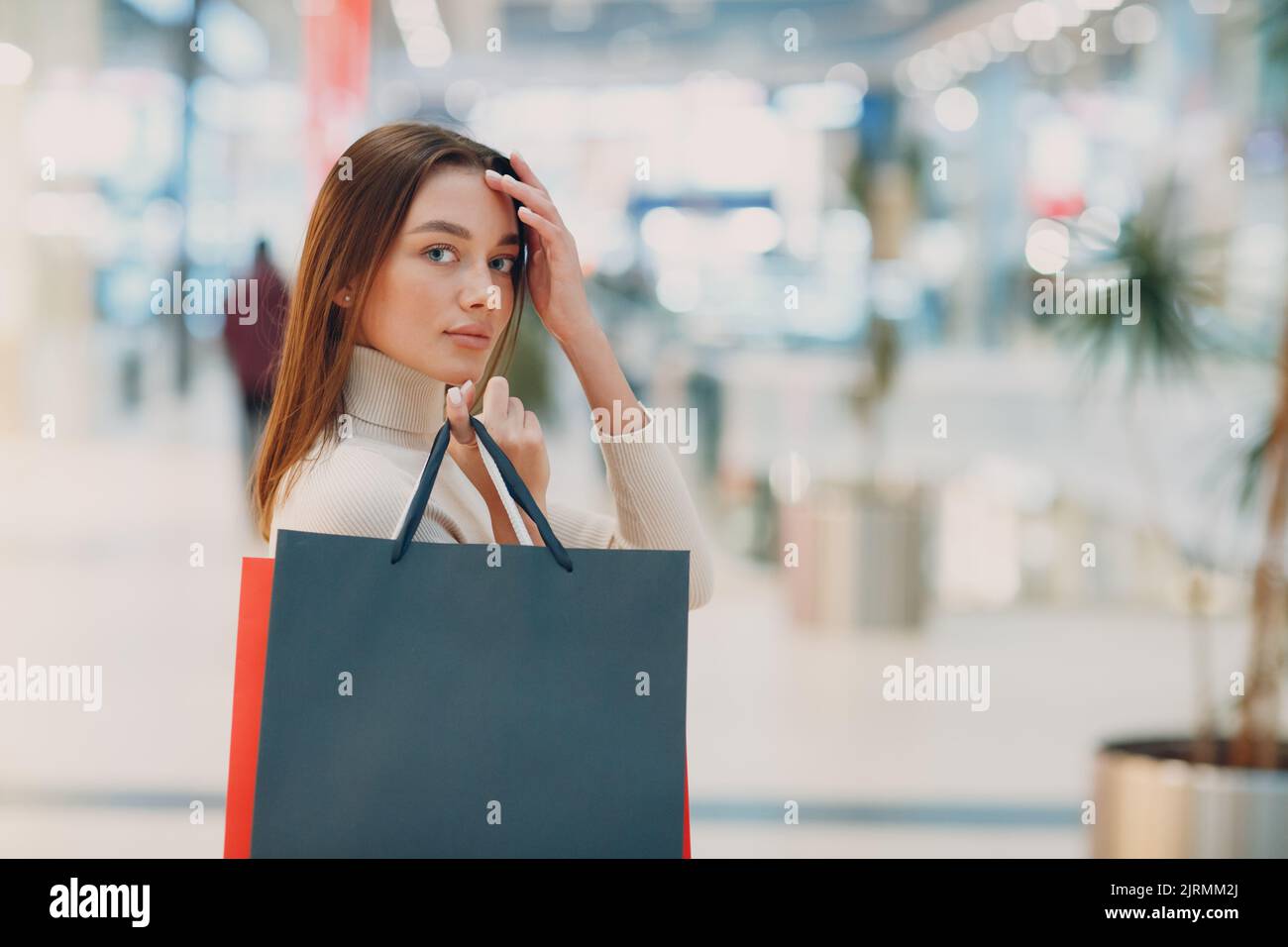 Positive young adult woman carrying paper shopping bags Stock Photo - Alamy