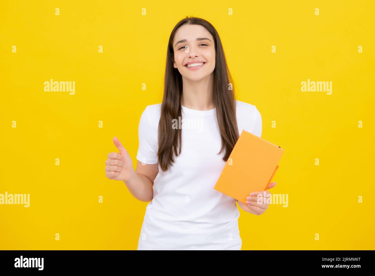 Smiling young woman college student holding book on isolated gray ...