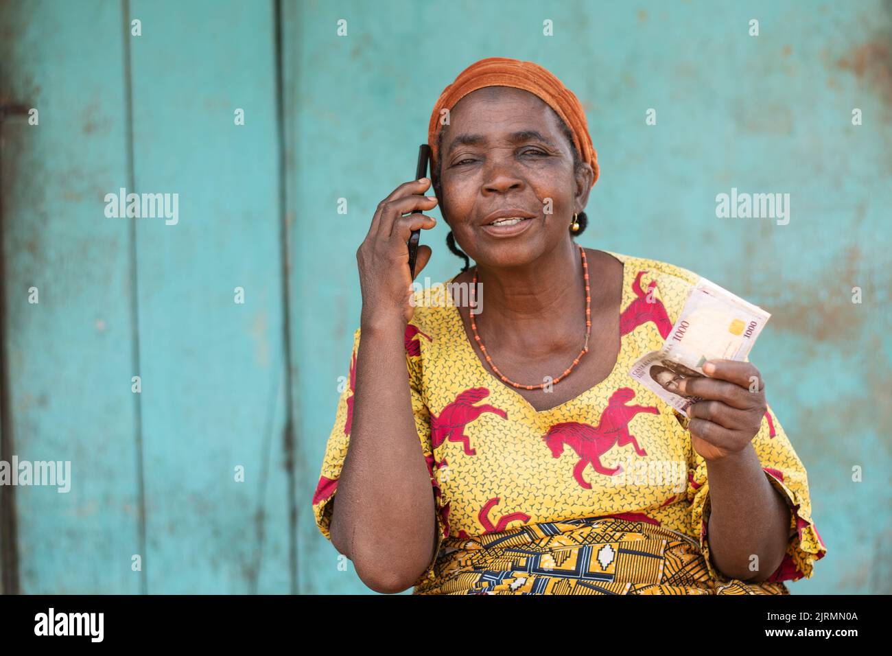 elderly african woman holding some money, making phone call Stock Photo ...