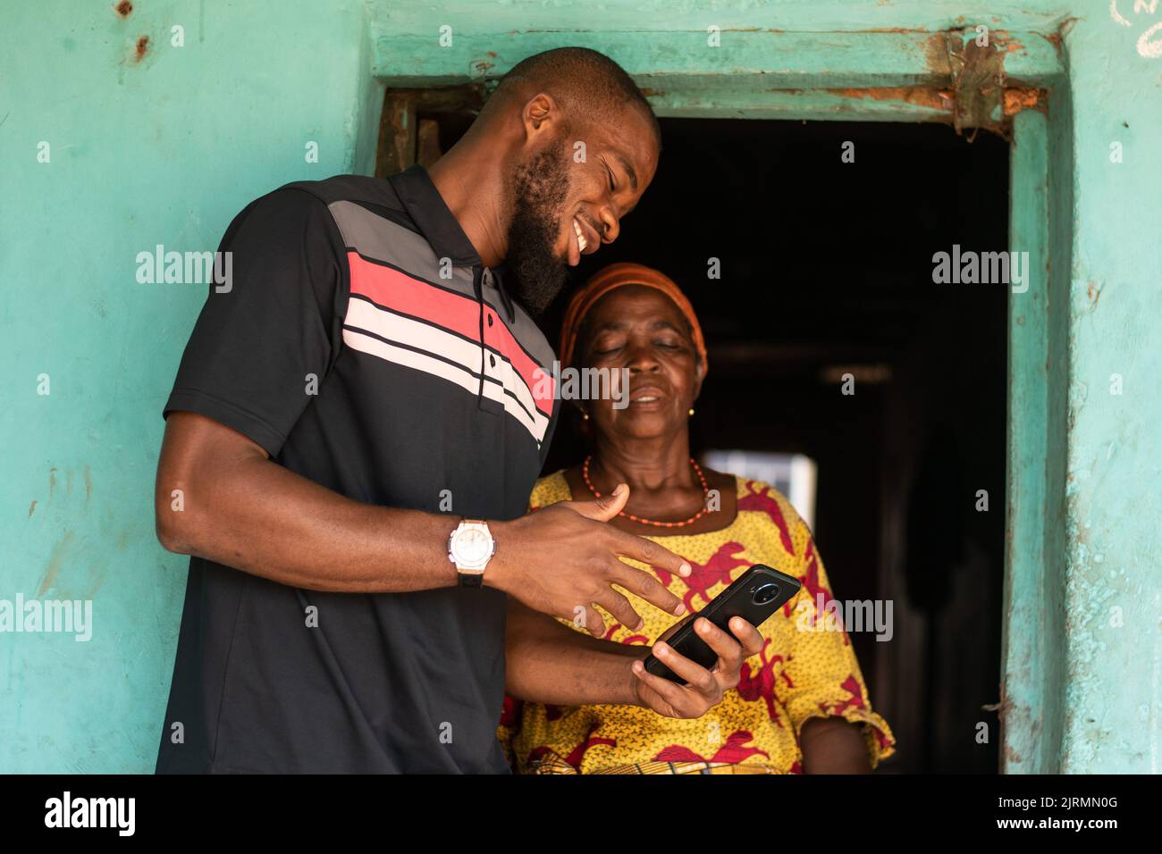 african man explaining to an elderly african woman with phone Stock ...