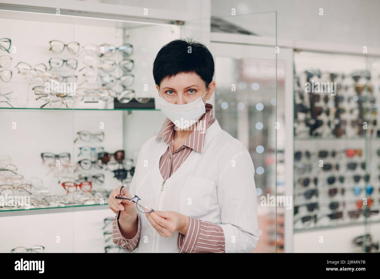 Happy Optician in Medical Face Mask Choosing Eyeglasses, female ...