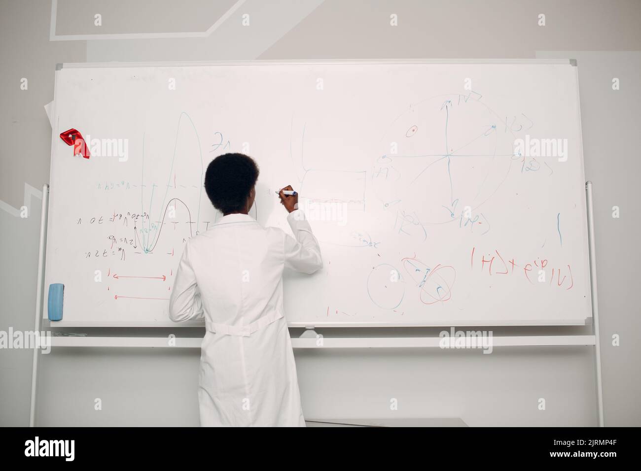 African American woman math teacher writing on whiteboard with marker ...