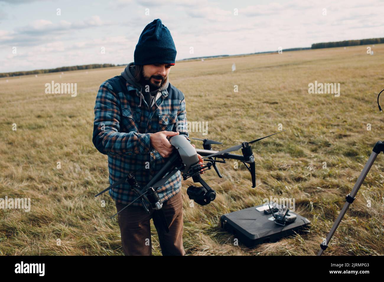 Man pilot checking quadcopter drone before aerial flight and filming ...