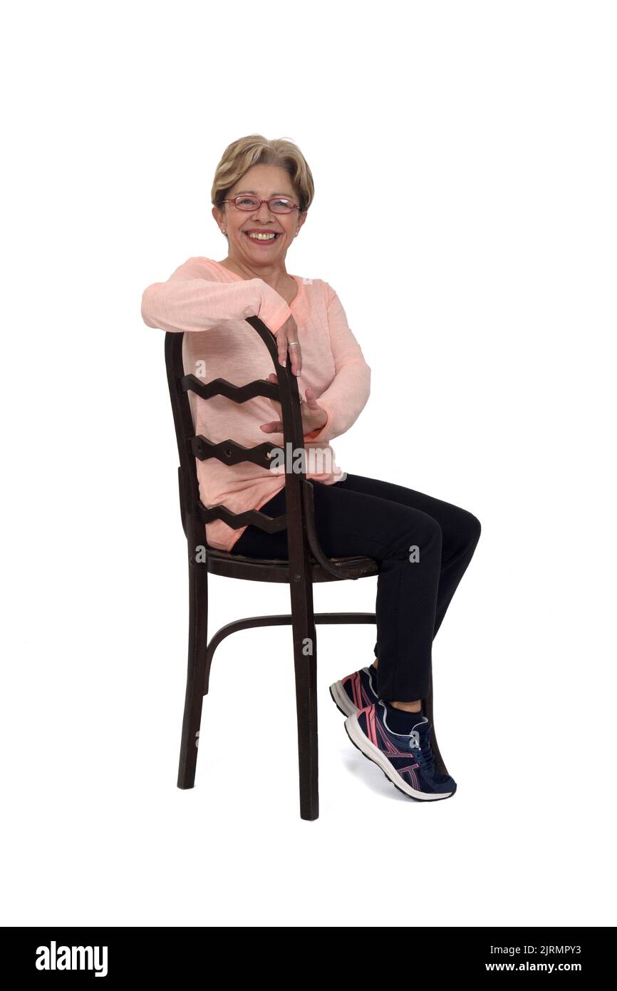 senior woman turned and sitting on chair dressed in sportswear on white ...