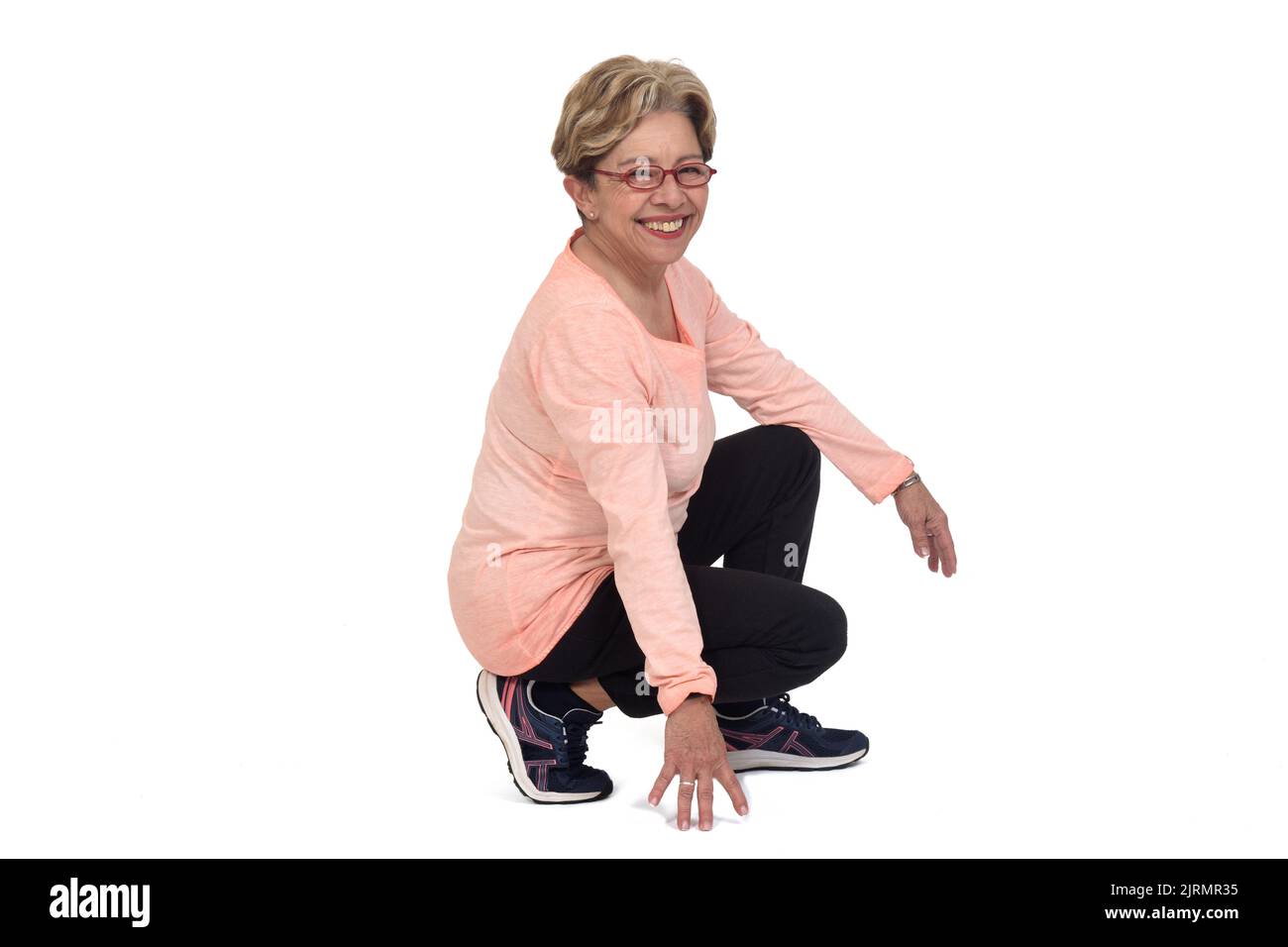 side view of a happy senior woman squatting and looking at camera on ...