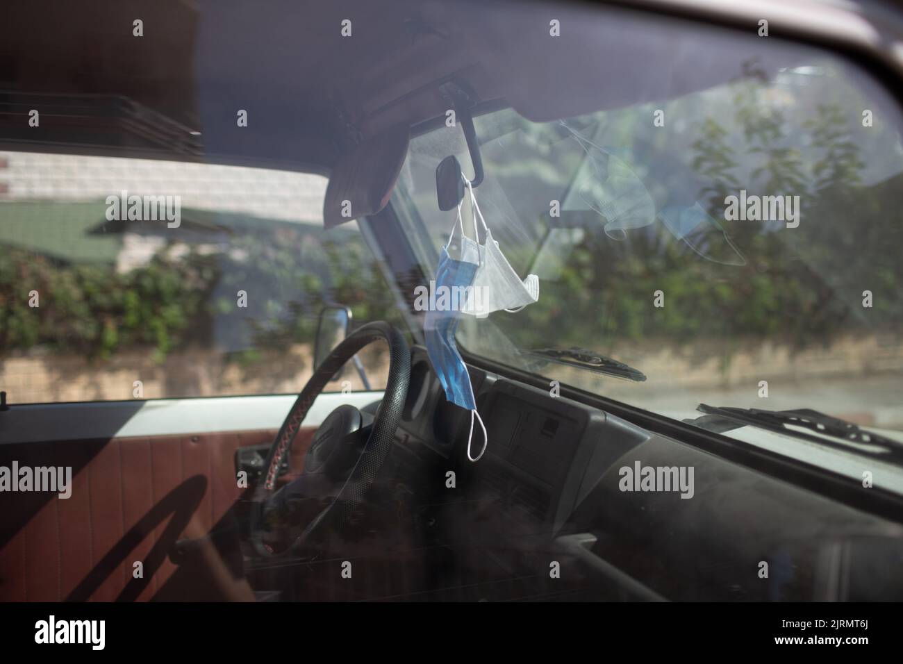 Face antiviral medical protective mask hanging in a car interior during ...