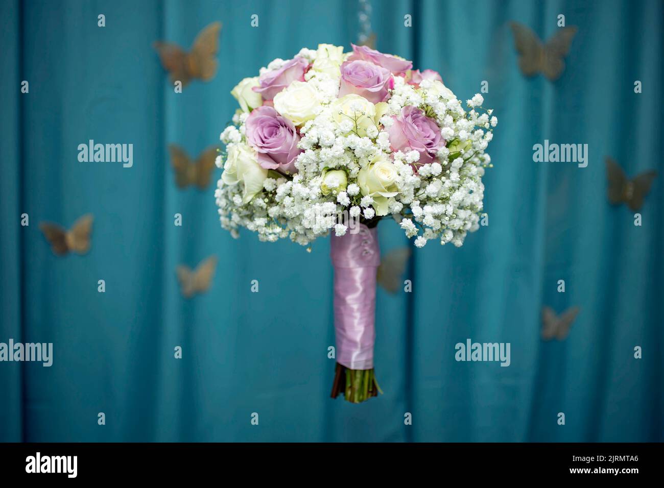 Bridals bouquet with purple roses, levitating on blue fabric folds ...