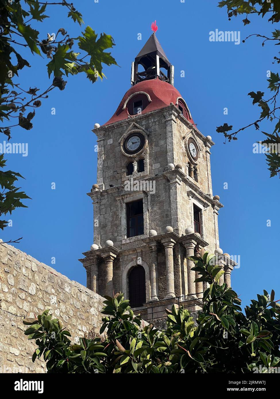 A medieval clock tower surrounded by trees in Rhodes town Stock Photo ...