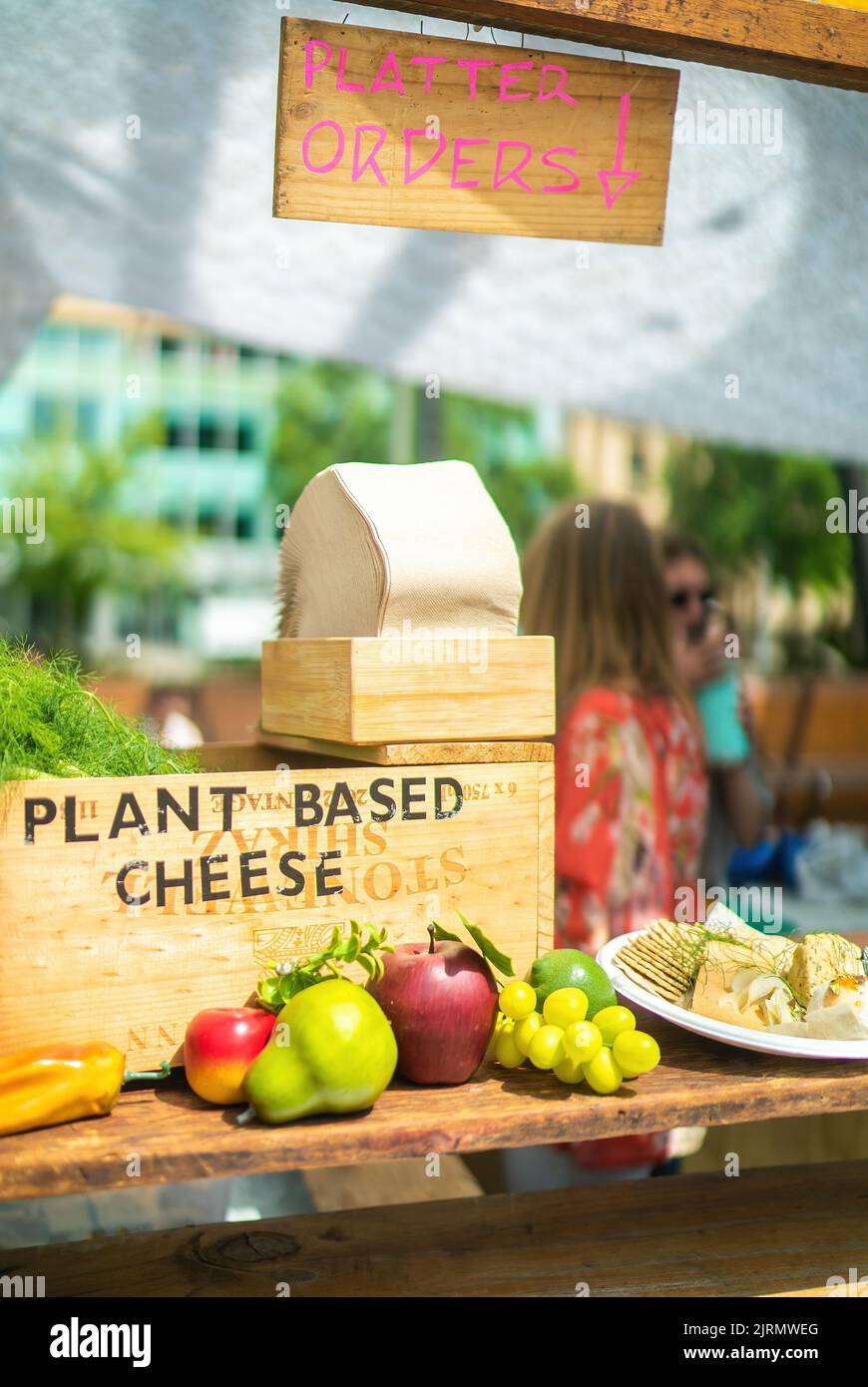 A vertical closeup of a stall selling plant-based cheese products at ...