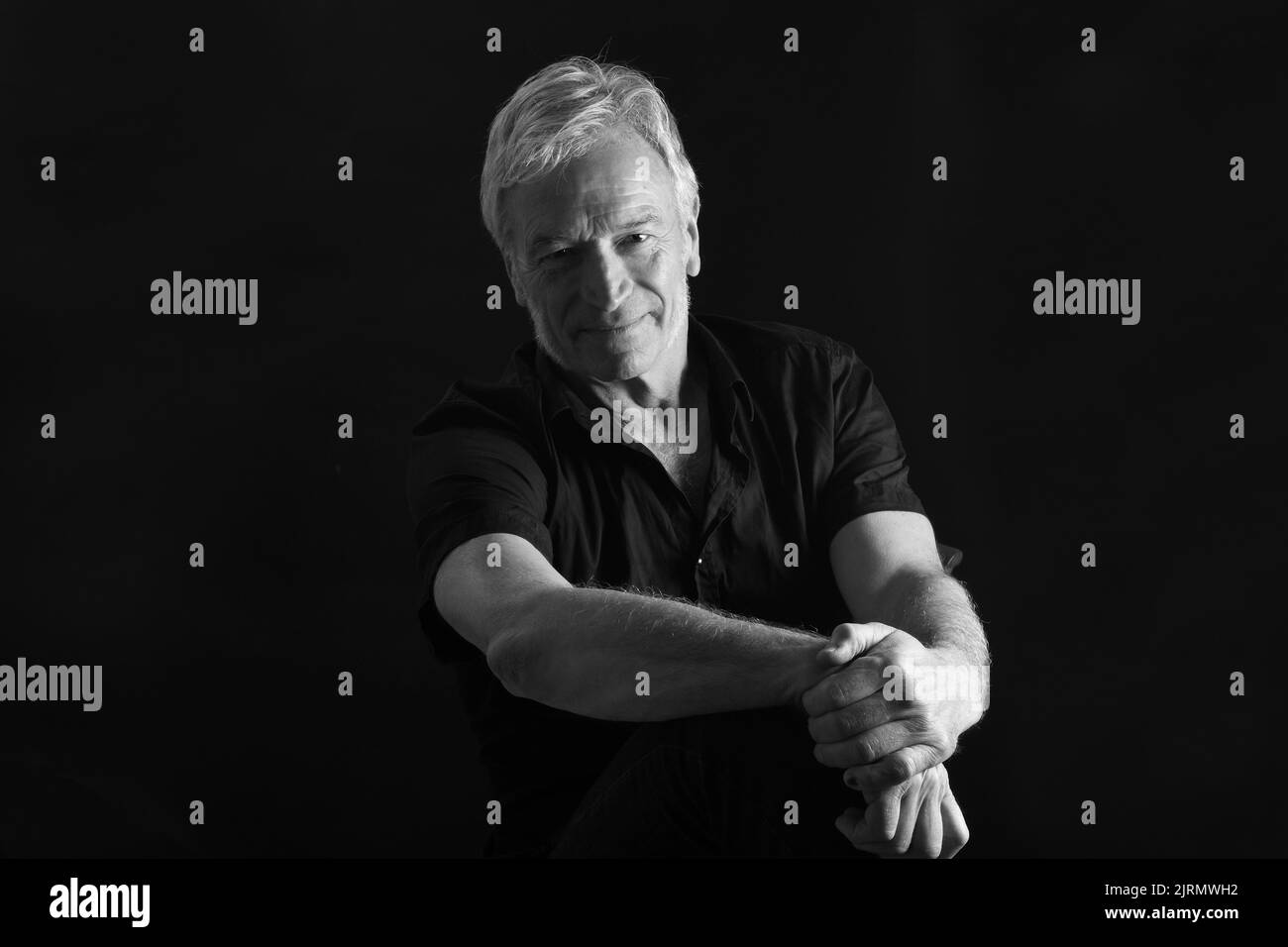 low key portrait of a senior man sitting a chair looking at camera on ...