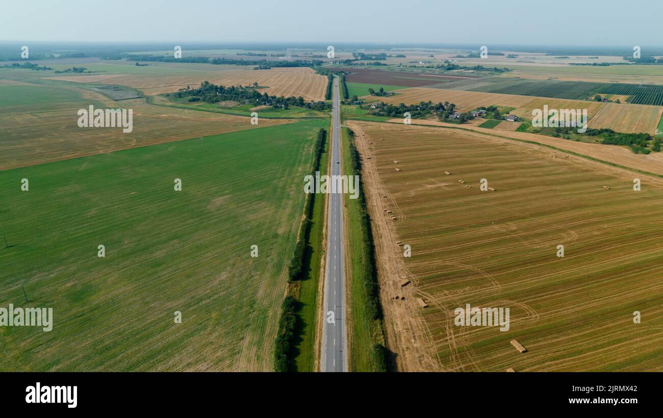 Aerial view of straight road with car between agricultural fields. View ...