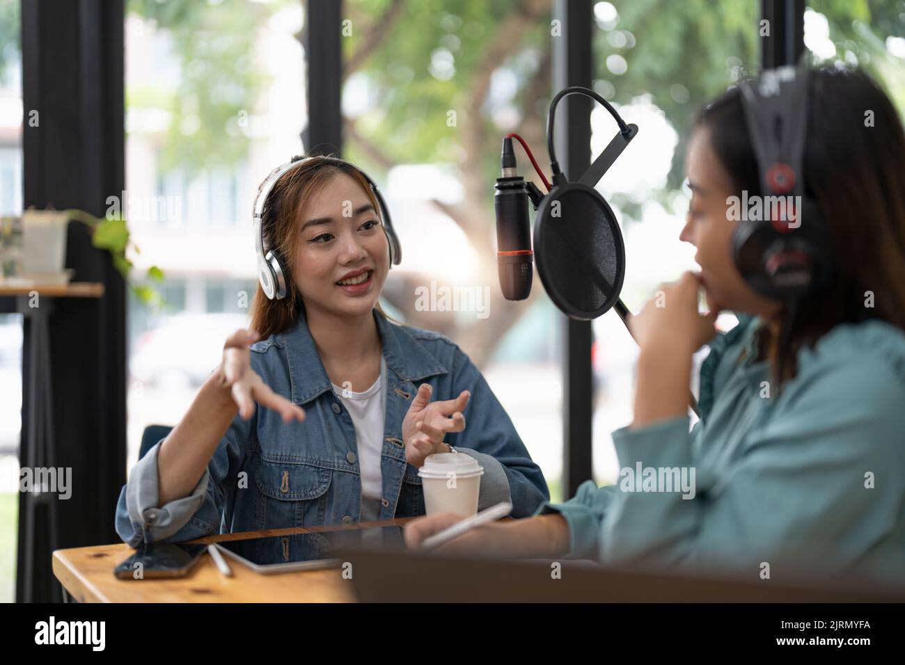 Female host recording radio podcast interview with guest at home office ...